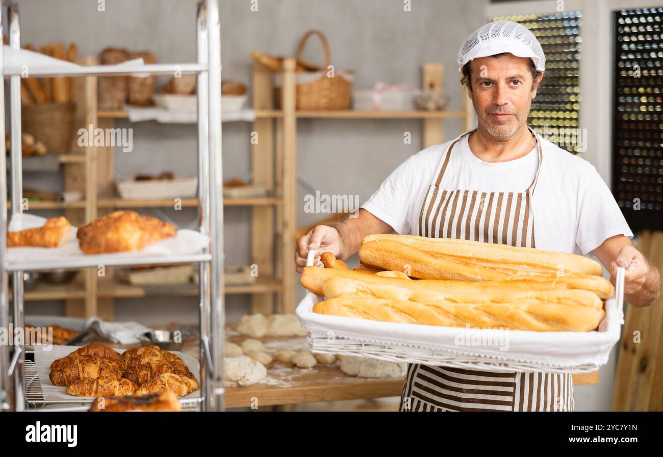 Adult male baker with basket of baguettes Stock Photo - Alamy