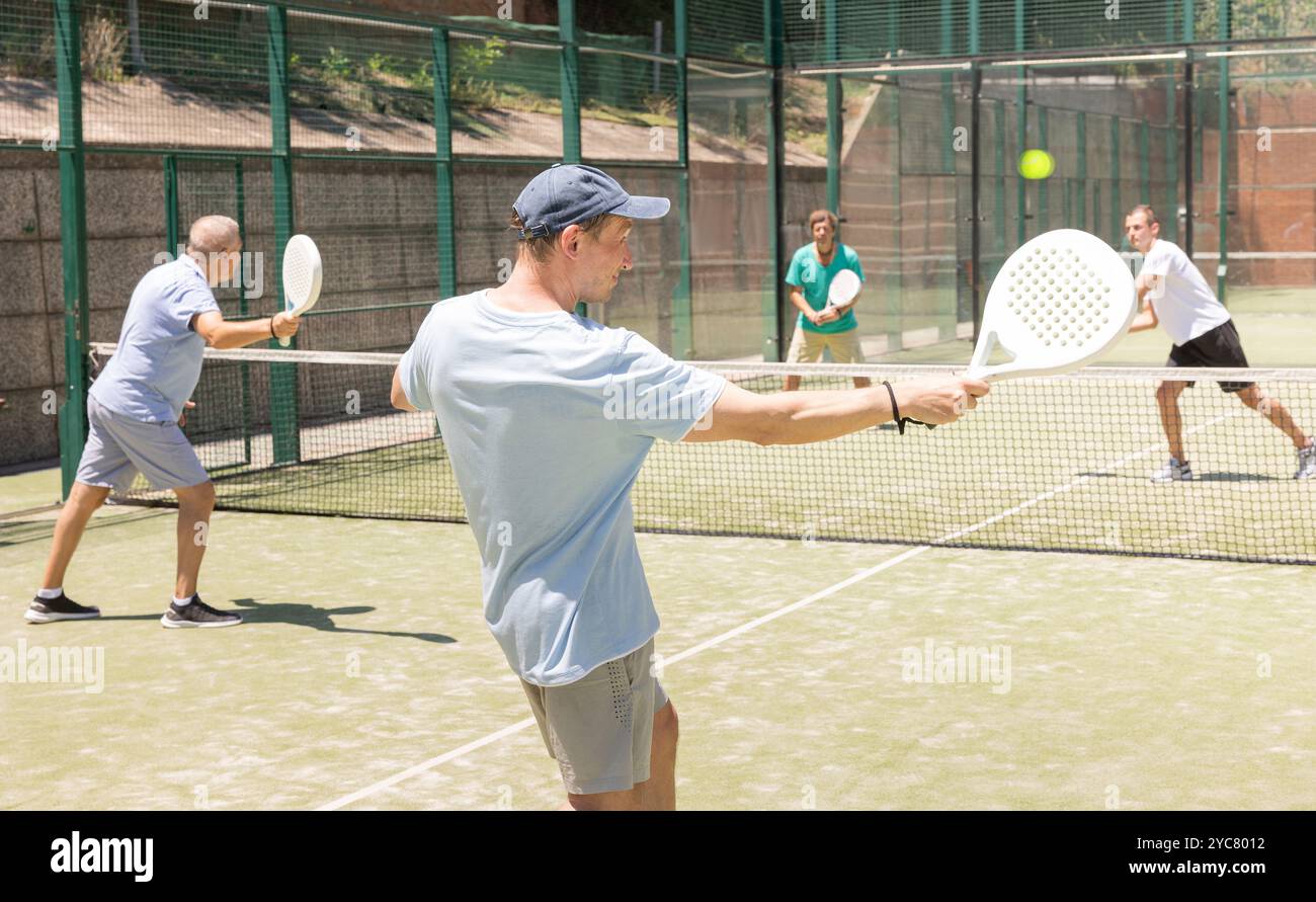 Four men practice playing padel on an outdoor court Stock Photo - Alamy