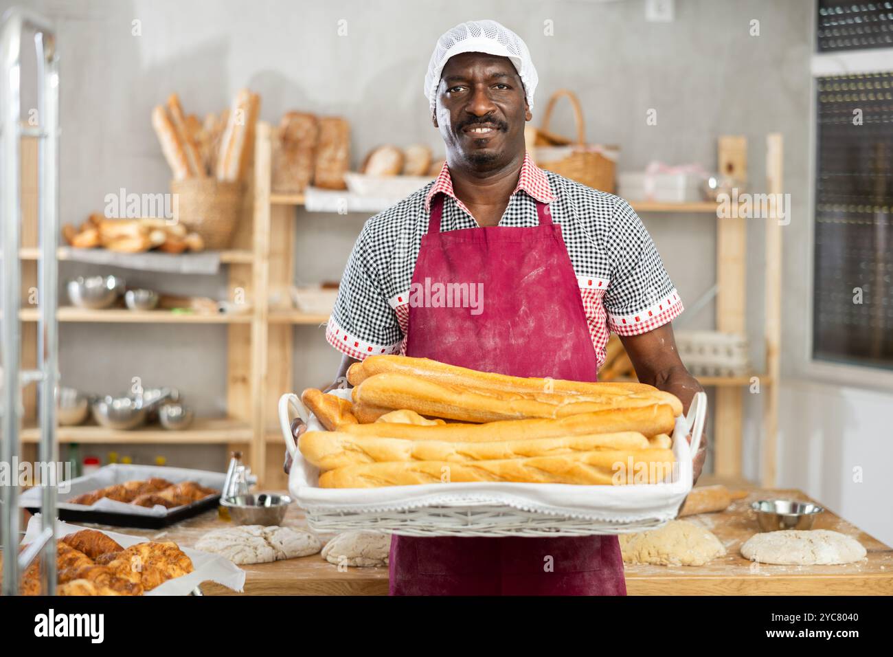 Successful African baker presenting golden baguettes in bakery Stock ...
