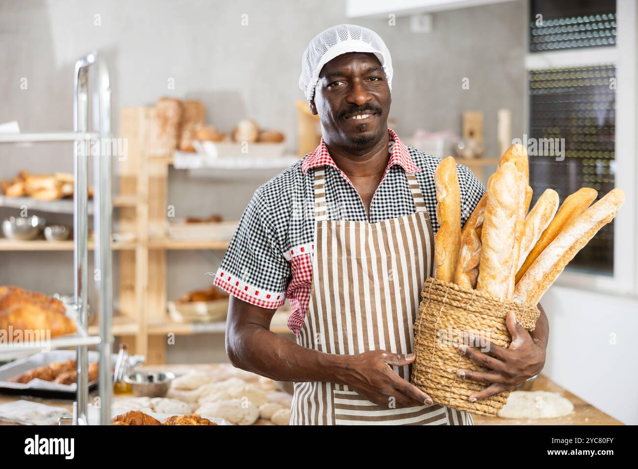 Successful African baker holding freshly baked baguettes Stock Photo ...