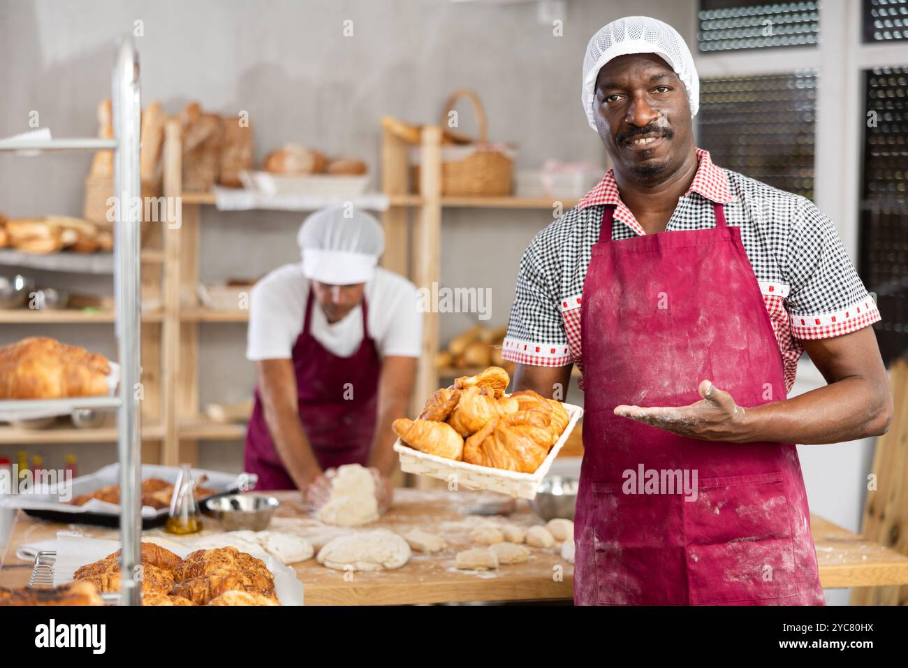 Smiling African baker offering freshly baked croissants in bakery Stock ...