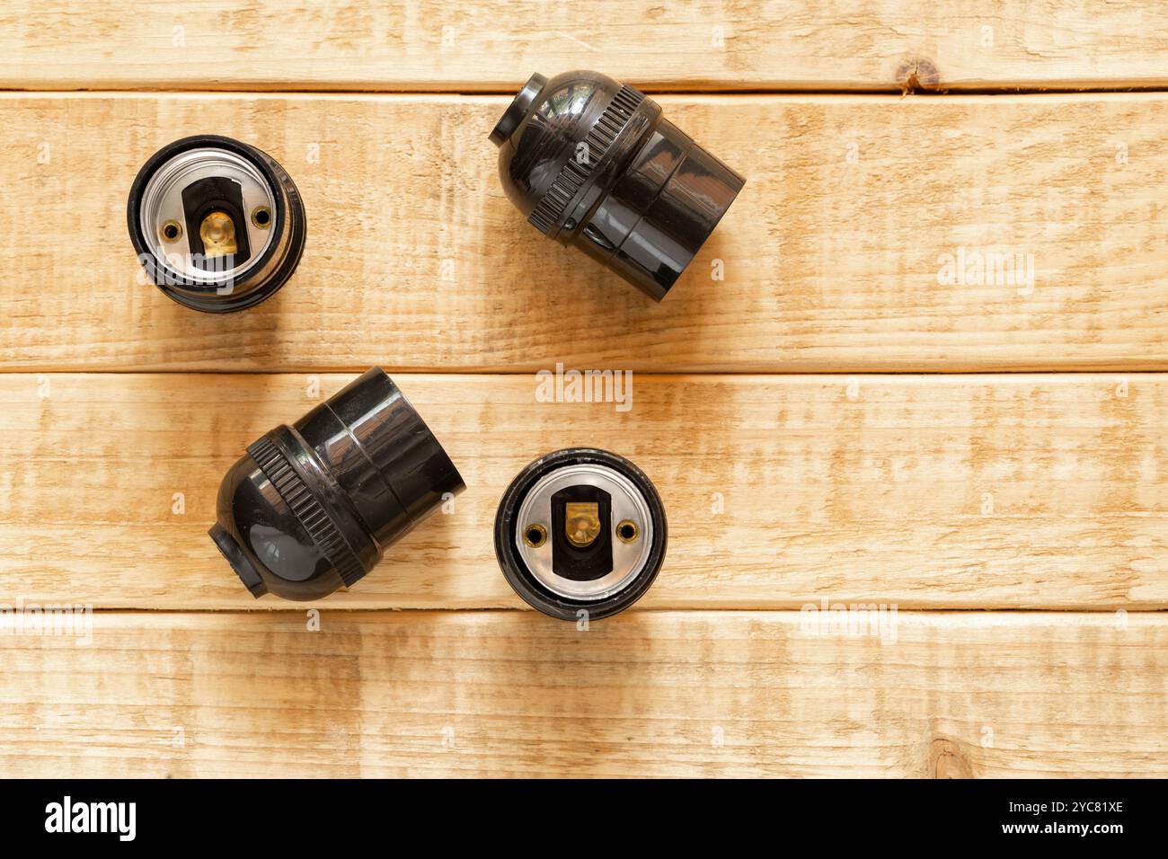 Four black light bulb sockets are scattered on a wooden surface ...