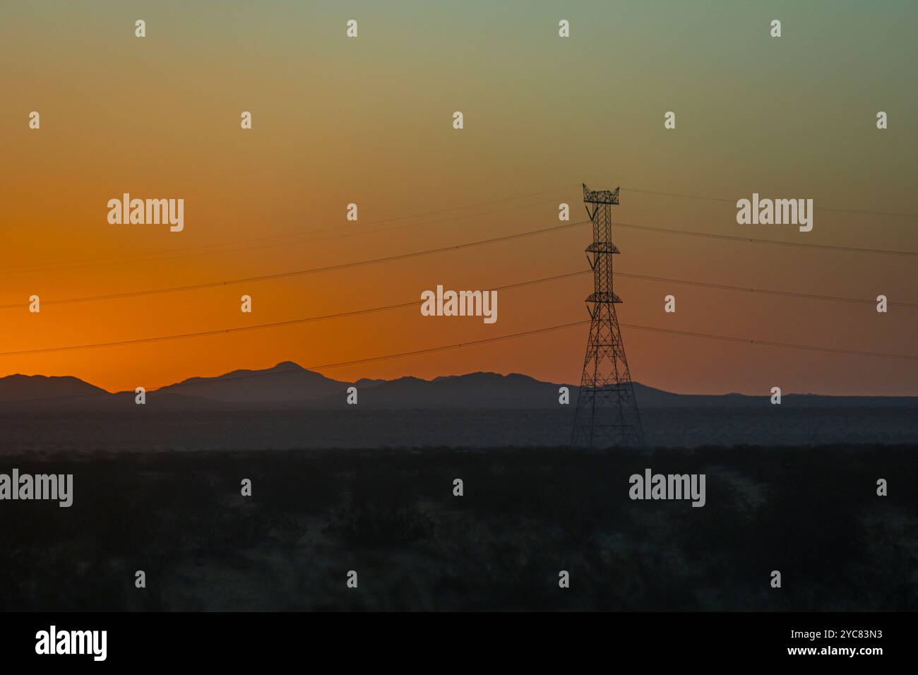 High voltage electricity or power lines and cables backlit at sunrise ...