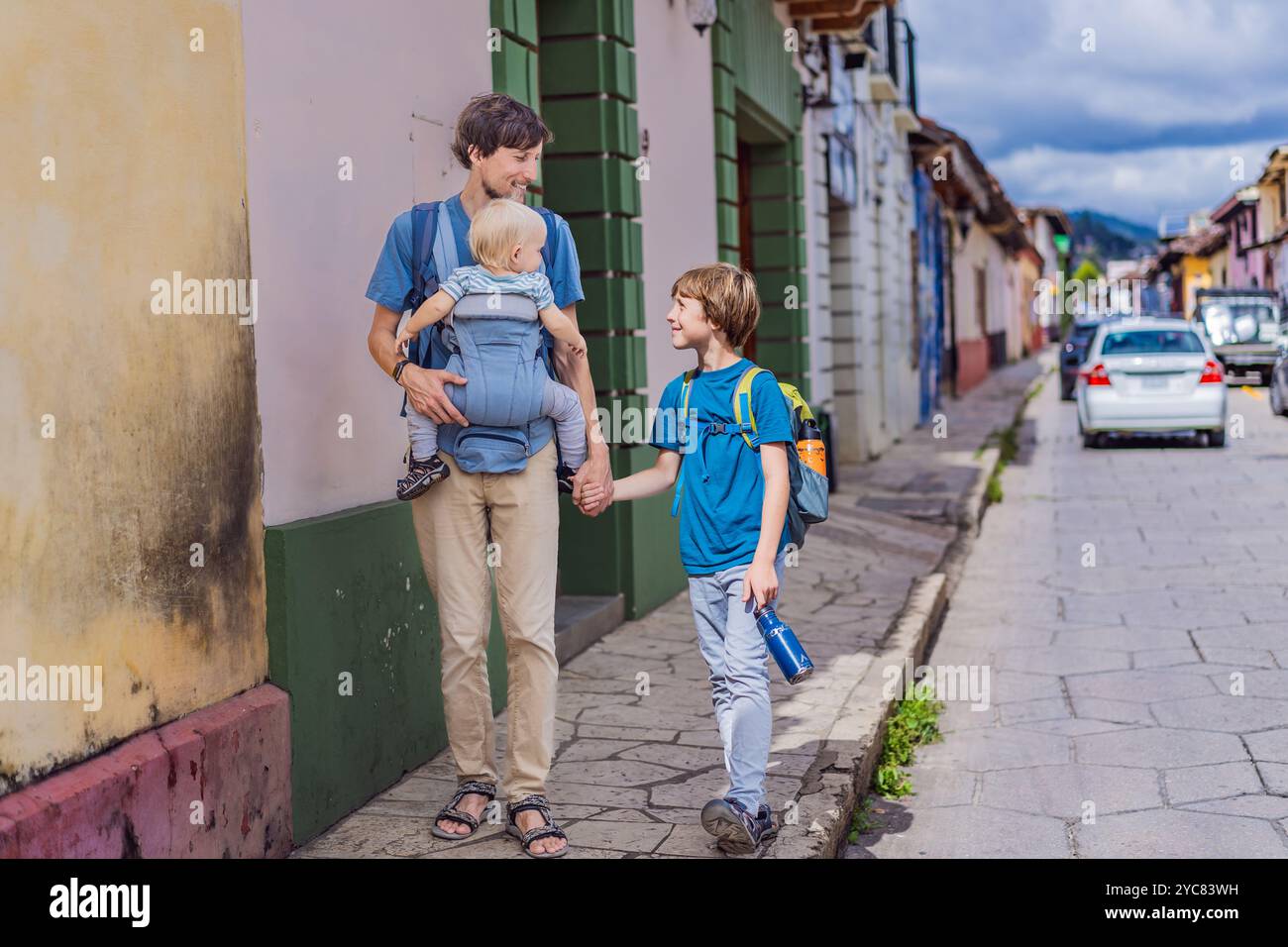 Father and and his two sons, a teenager and a baby tourists walks ...