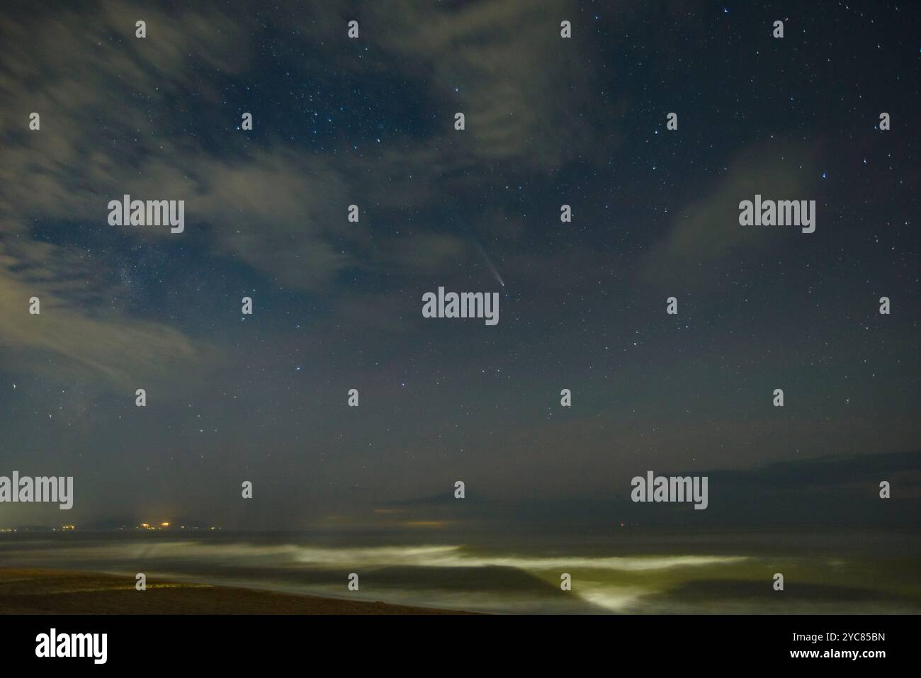 The coastal sunset turns into a starry night. In the sky comet C/2023 ...