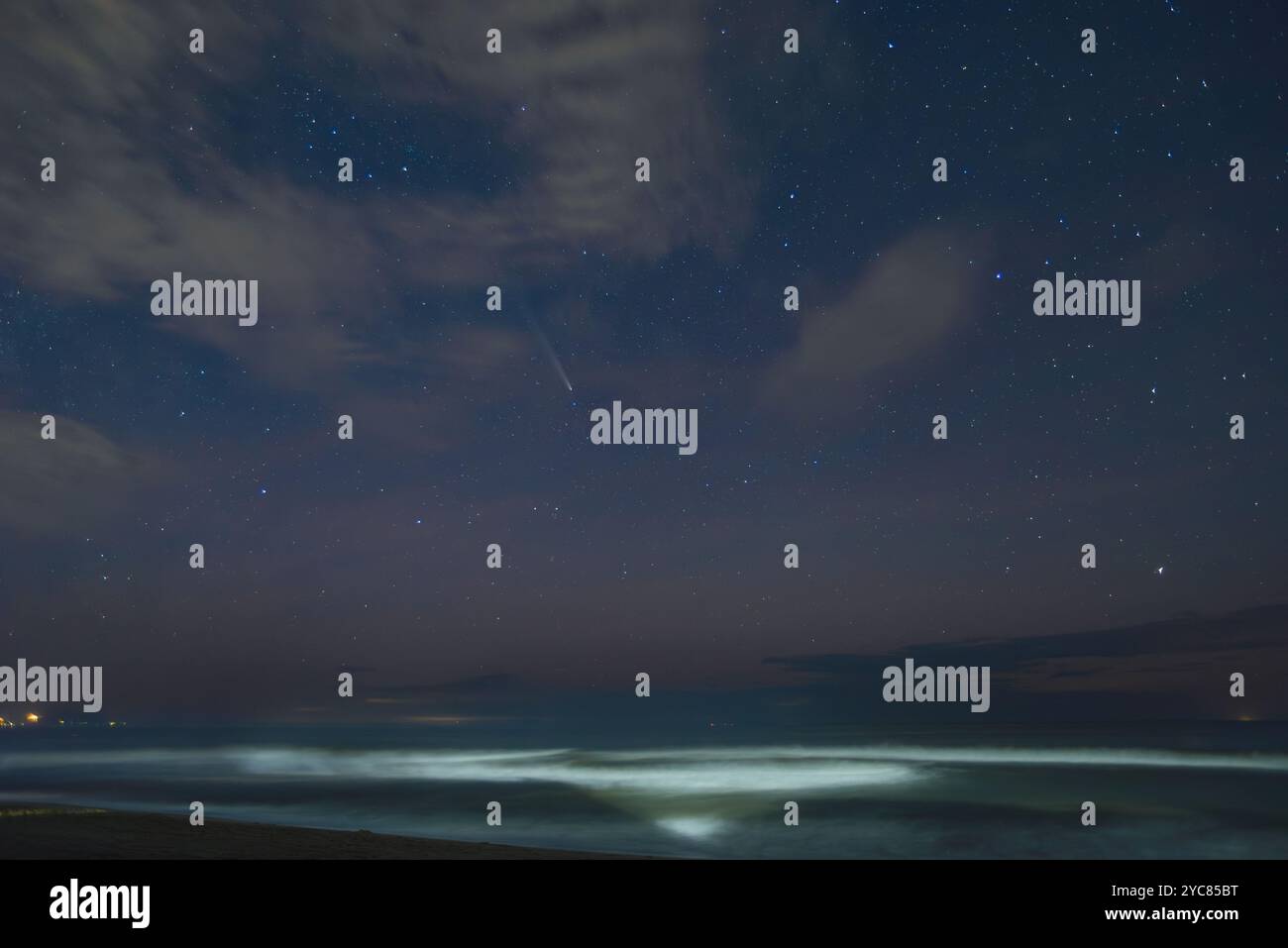 The coastal sunset turns into a starry night. In the sky comet C/2023 ...