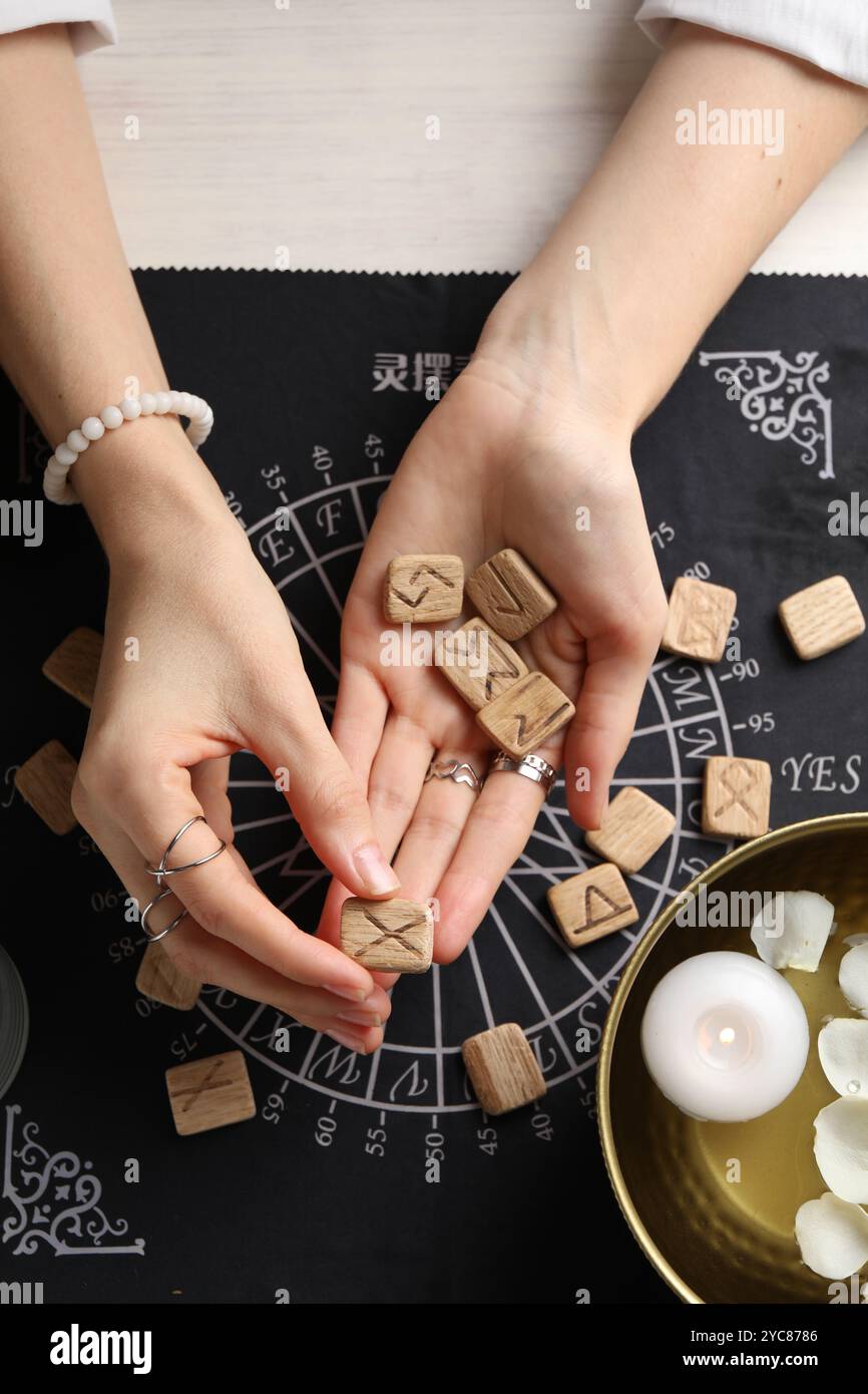 Woman with wooden runes at table, top view Stock Photo - Alamy