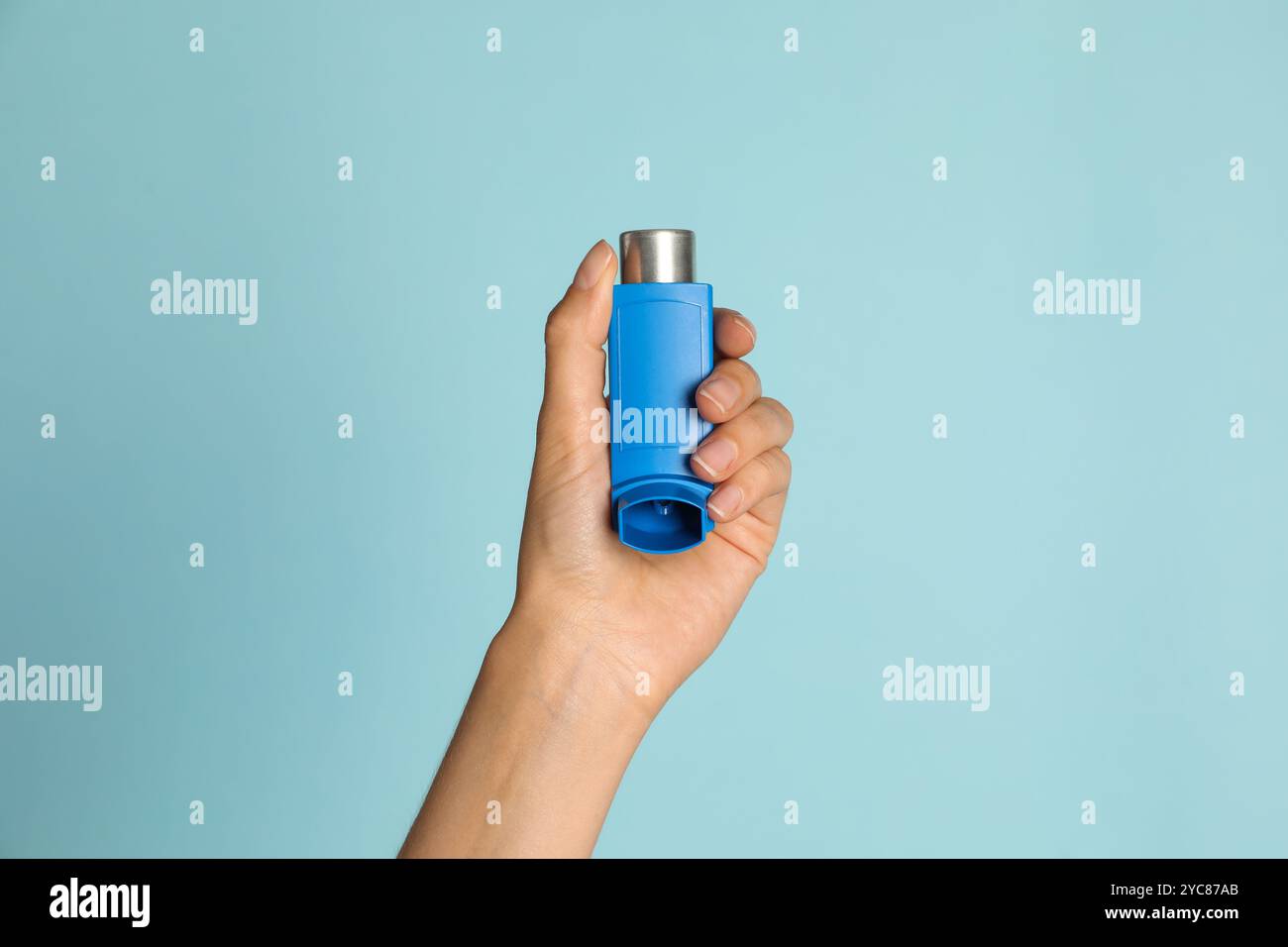 Woman holding asthma inhaler on light blue background, closeup Stock ...