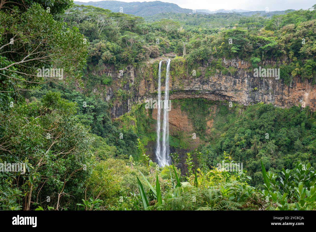 The majestic Chamarel Falls cascade down a steep cliff, surrounded by ...