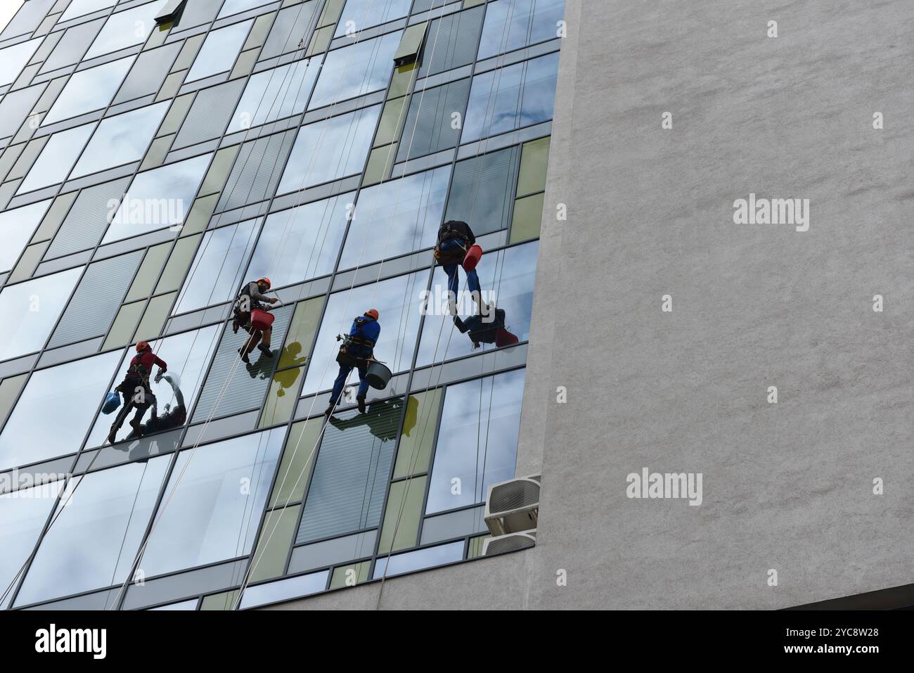 Glass facade skyscrapper window cleaners hanging on rope Stock Photo ...