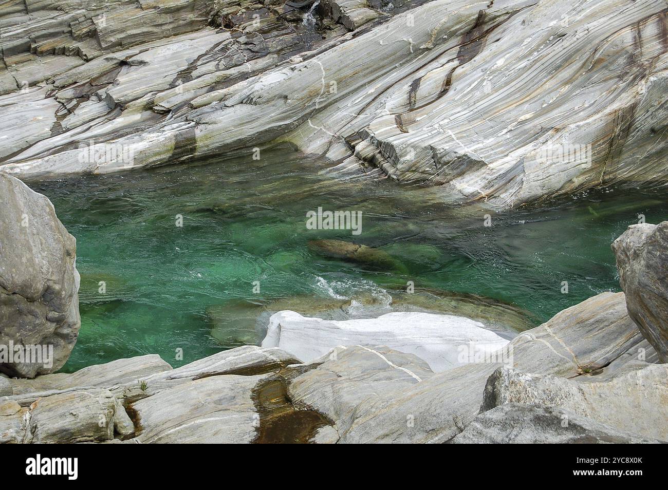 Fast flowing cold emerald water between the water-polished rocks in the ...