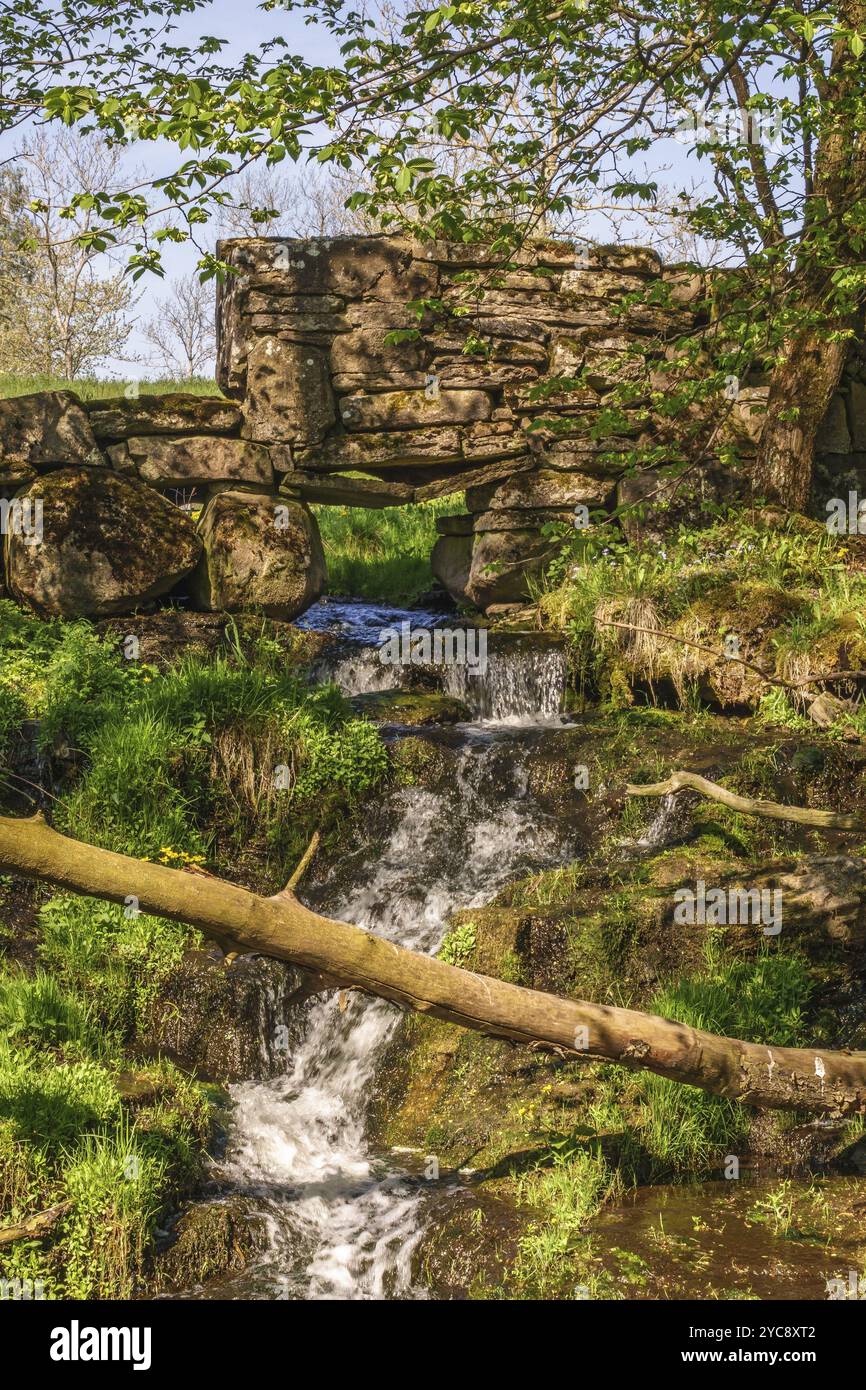 Waterfall in a stream at an old floodgate with a log of wood Stock ...