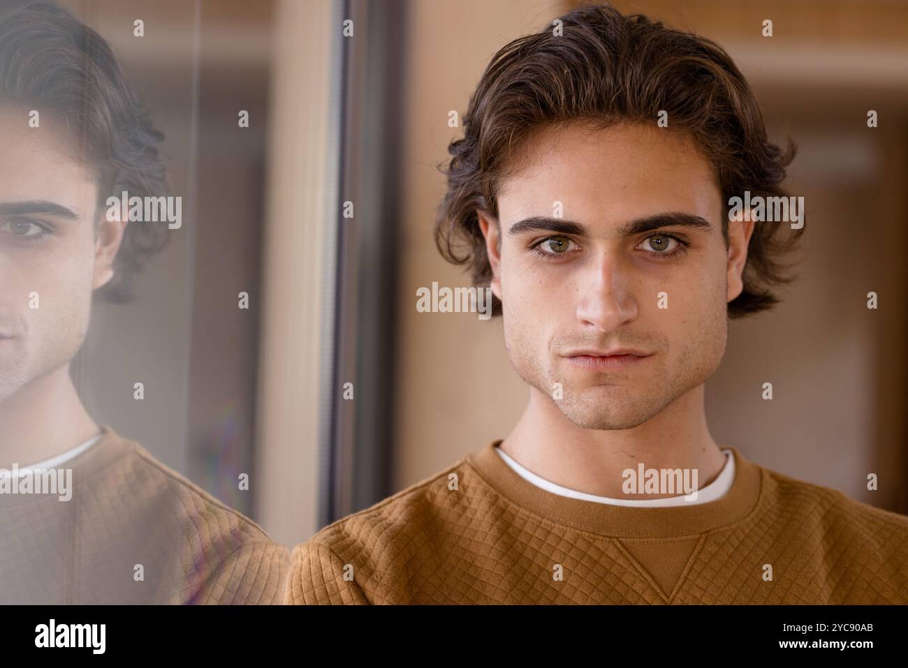 Standing by window, man reflecting thoughtfully at home, lost in ...