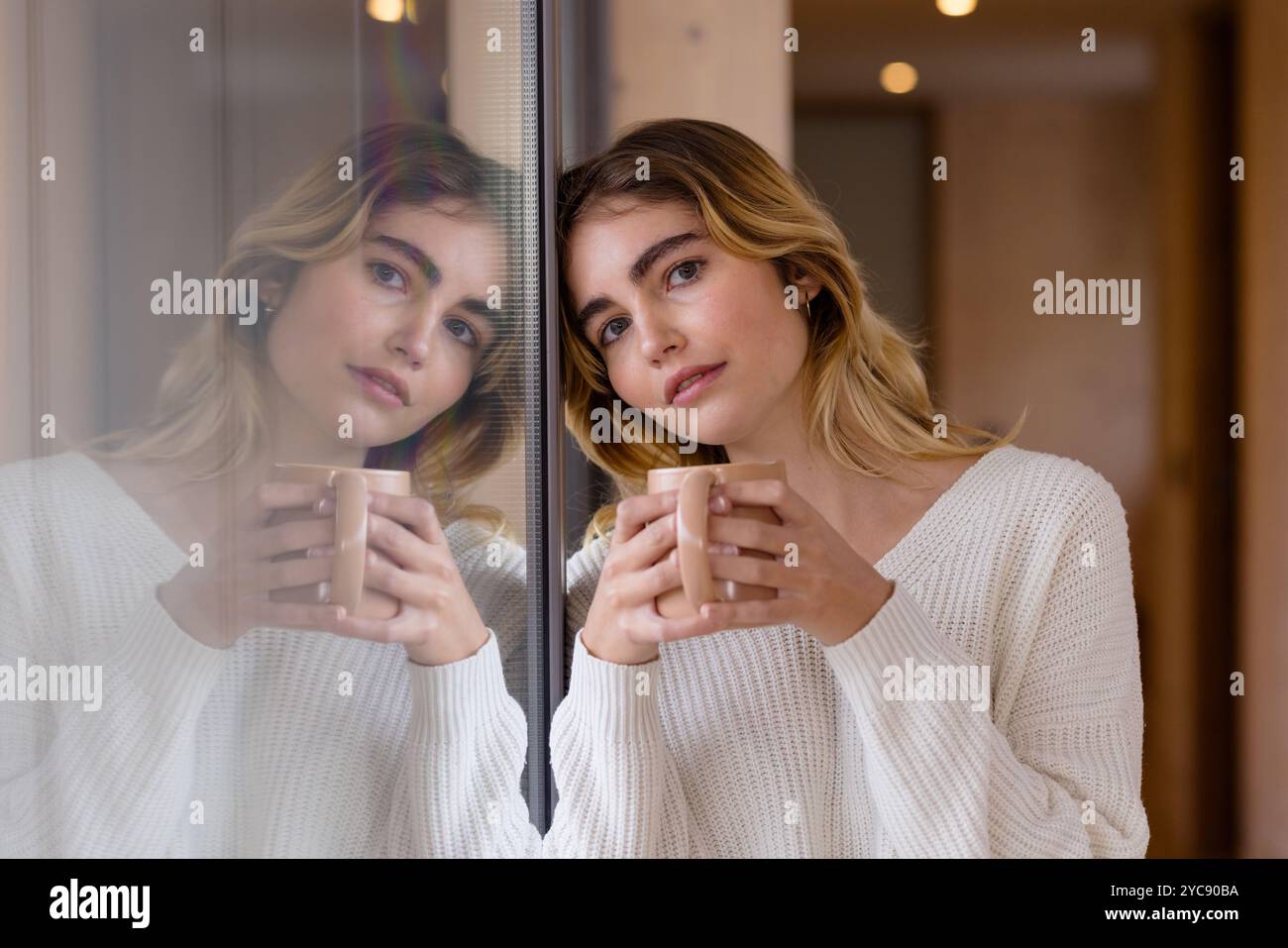 Woman relaxing with coffee by window, reflecting on cozy winter day, at ...