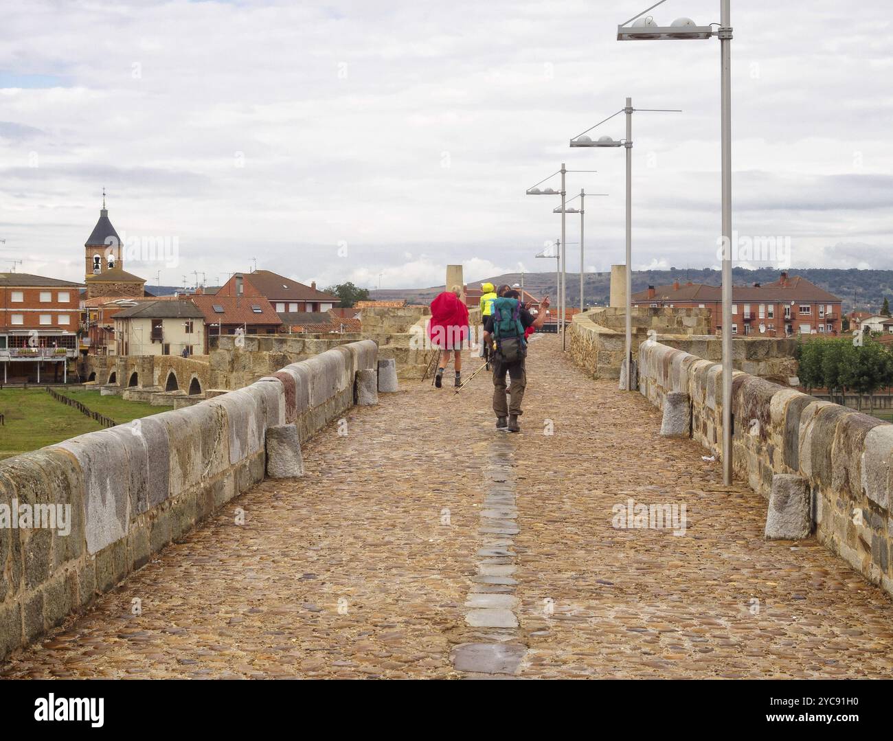 Pilgrims walk on the 13th century Medieval bridge over the Orbigo River ...