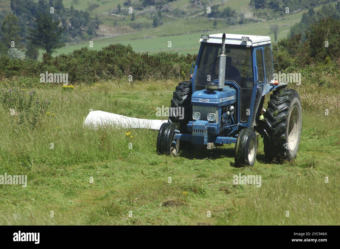Tractor mowing pasture for silage, West Coast, South Island, New ...
