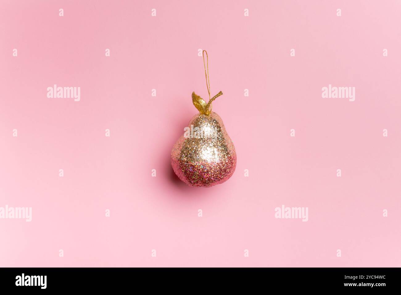 Christmas tree toy golden pear with sequins on a light pink background ...
