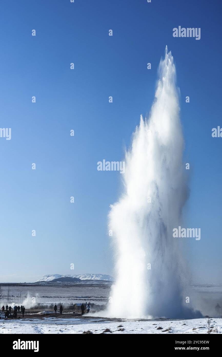 High jet of water from a geyser against a bright sky, surrounded by ...