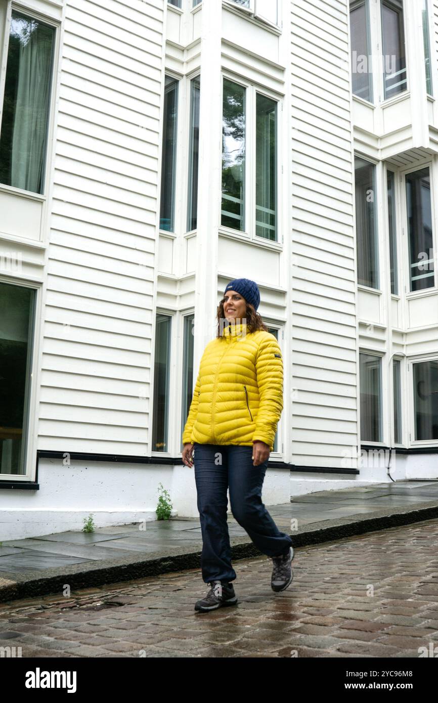 A young brunette woman, around 30 years old, walks in front of a white ...