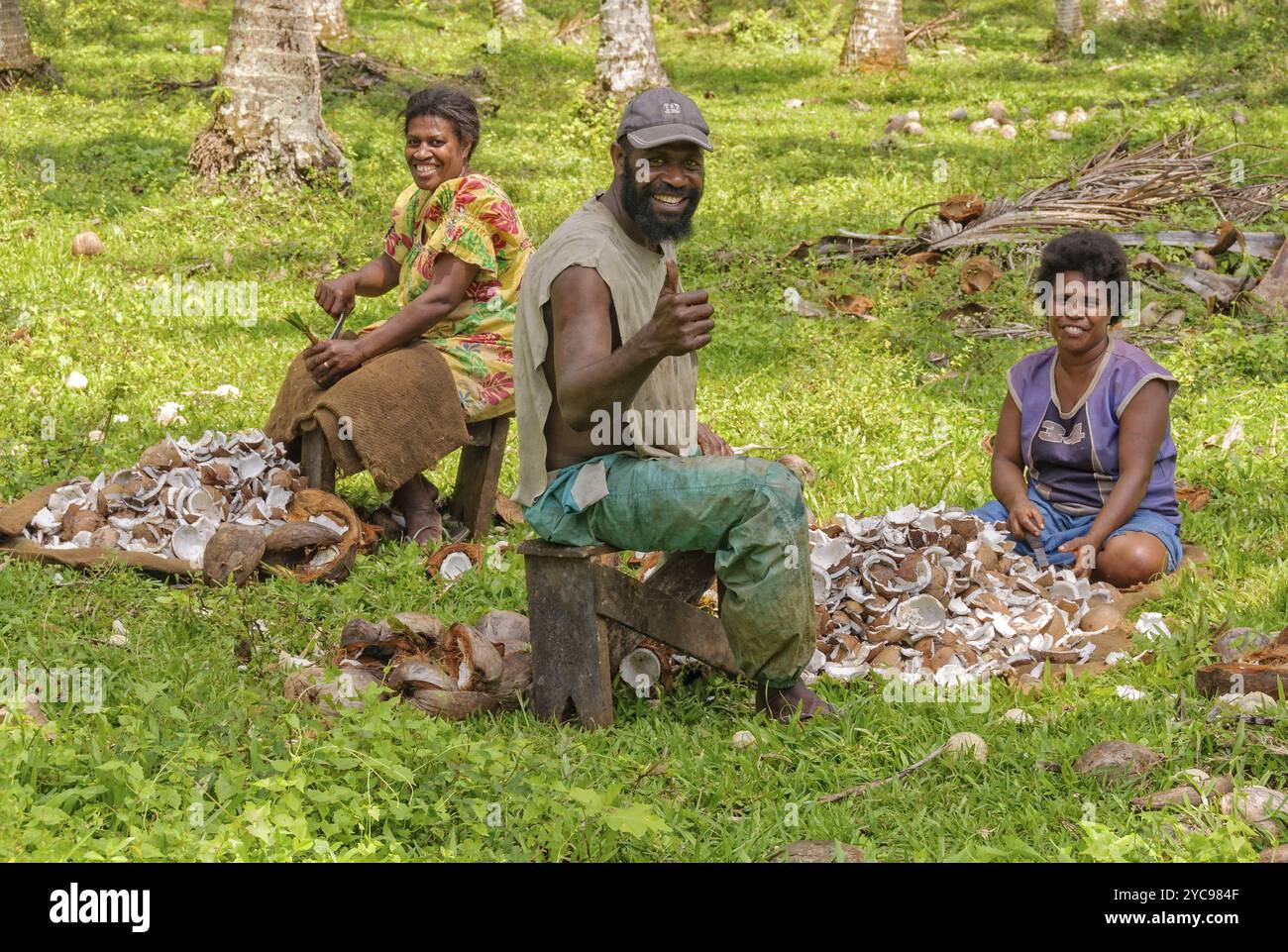 A family of three smile at the camera during coconut copra harvest ...