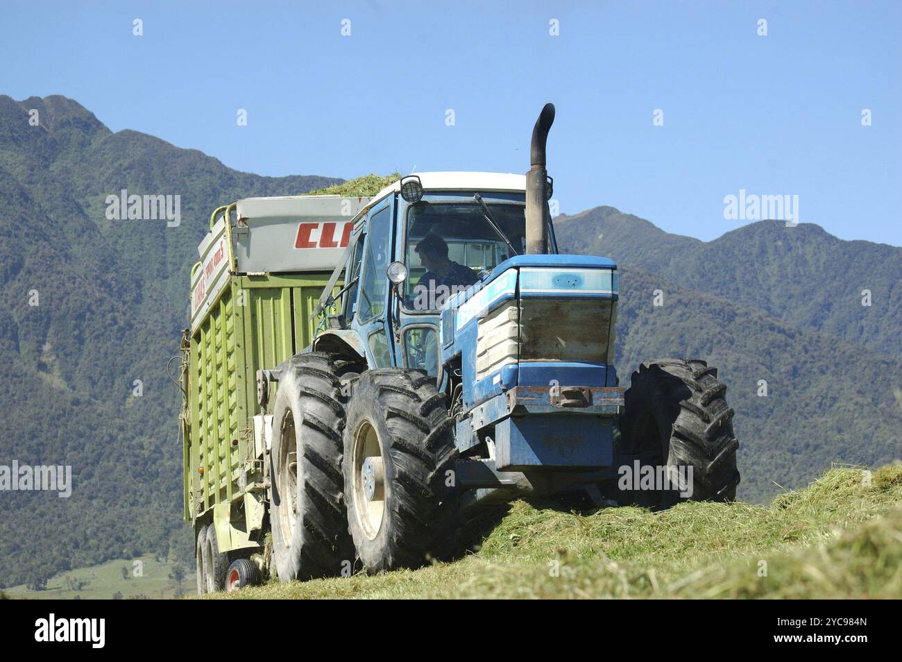 Greymouth, New Zealand circa 2008: Tractor picking up mown pasture in ...