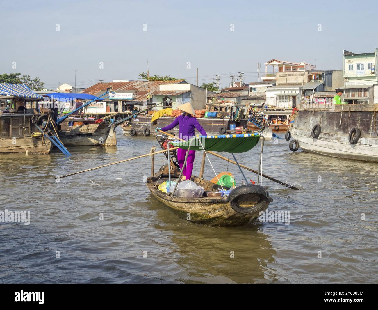 A woman is rowing her boat in the floating market on the Mekong River ...