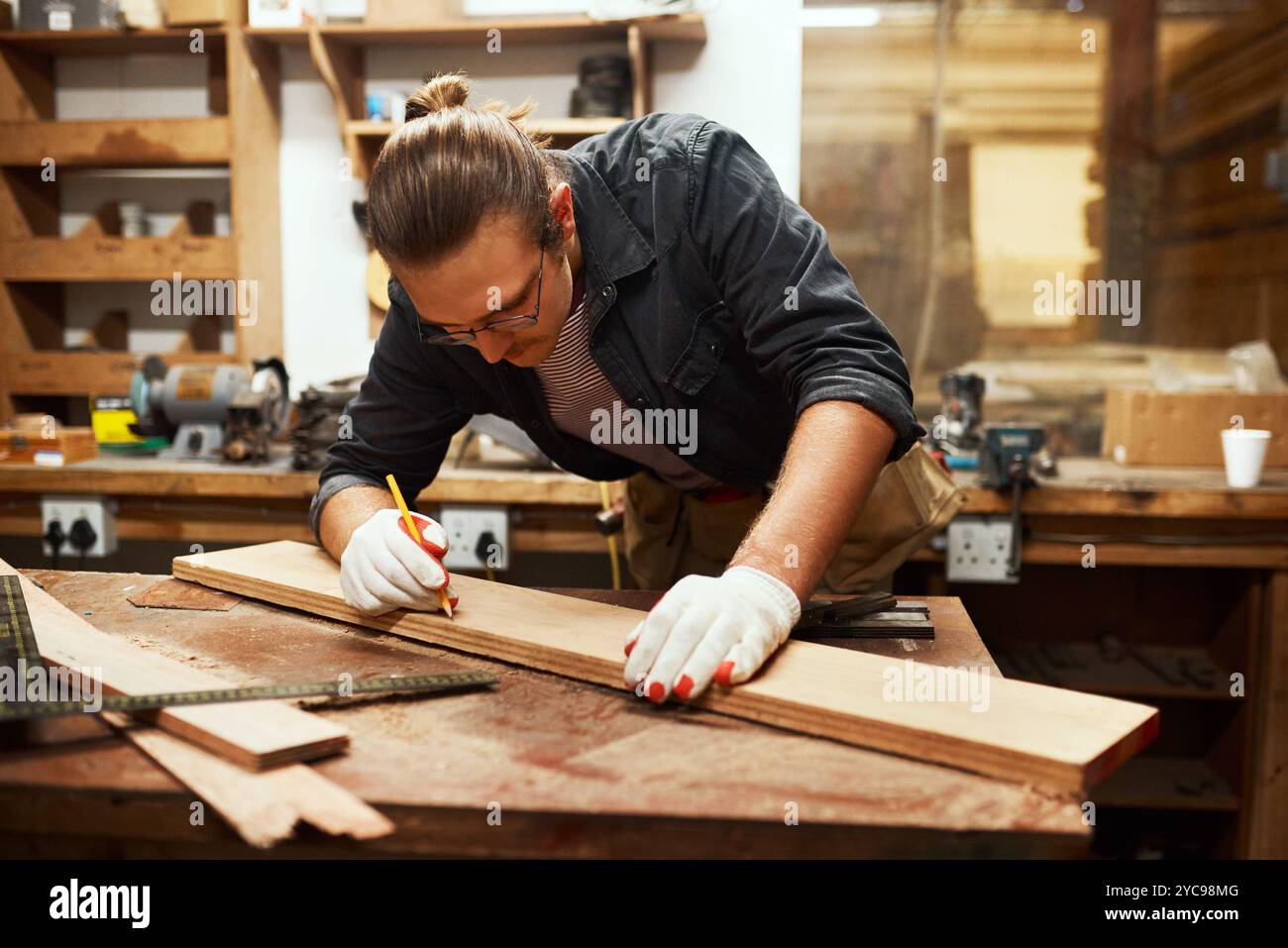 Man, building and pencil to measure wood at workshop, carpenter and ...