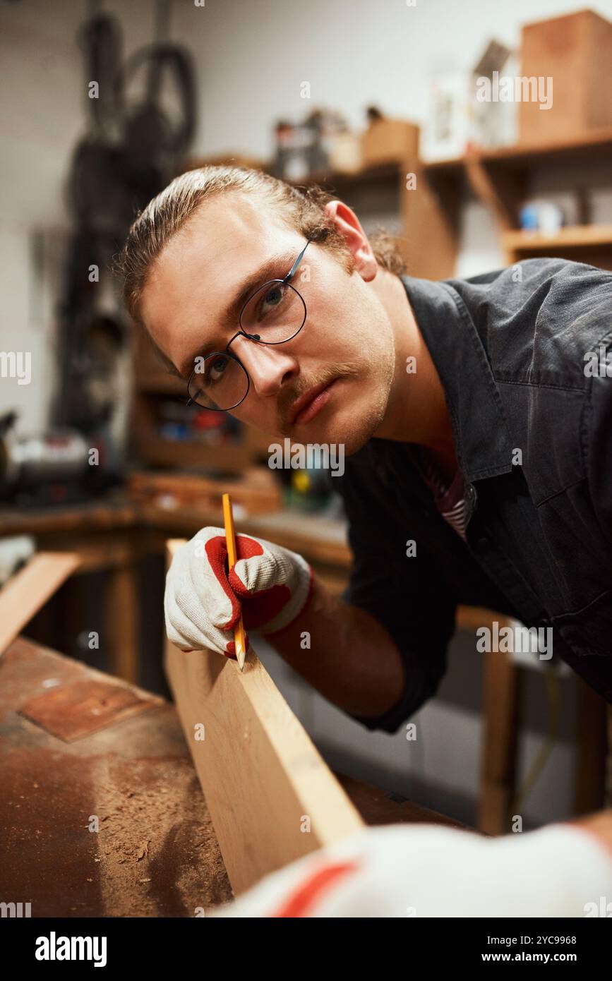 Man, portrait and pencil to measure wood at workshop, carpenter and ...