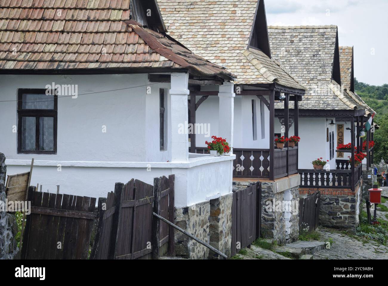 Row of farmhouses with porches decorated with flowers in Holloko ...
