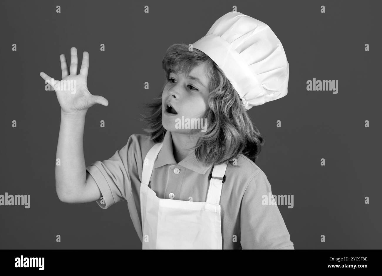 Child chef cook prepares food in isolated blue studio background. Kids ...