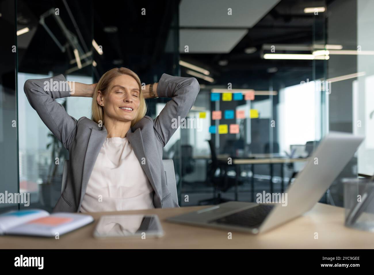 Confident mature business woman takes relaxing break in modern office ...