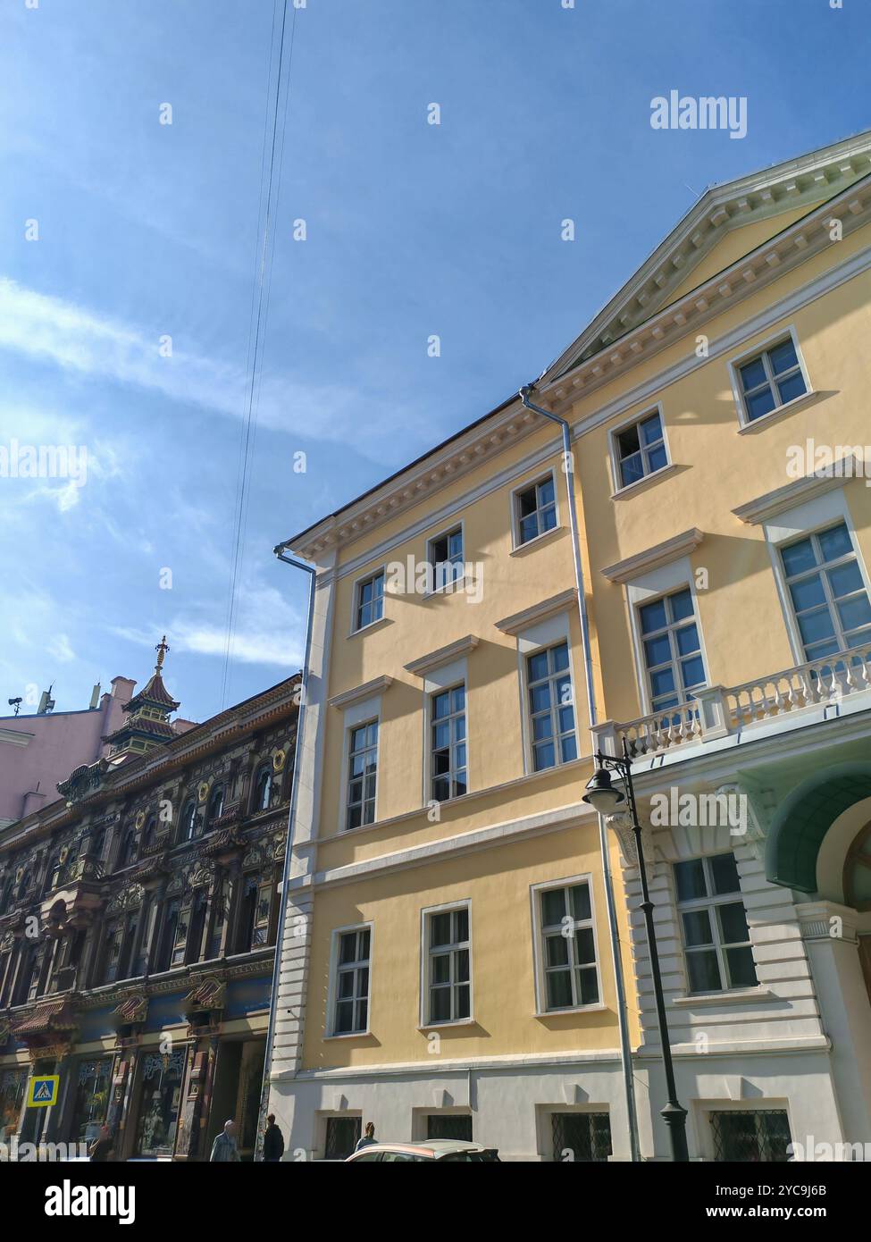 A three-story building with a pale yellow exterior and symmetrical ...