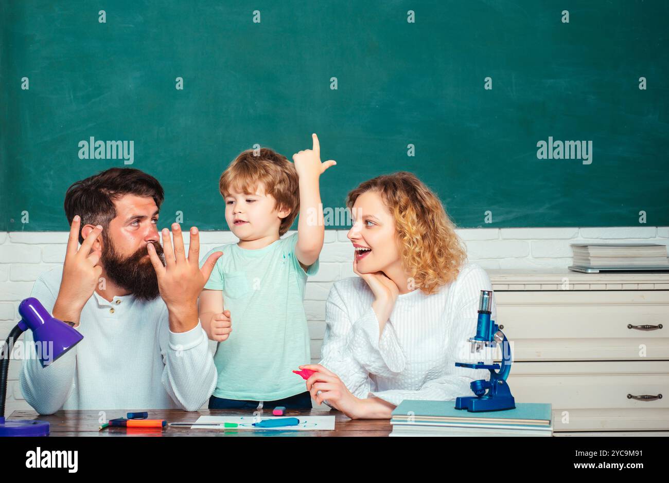 Cute pupil and his father and mother making schooling work. Family ...