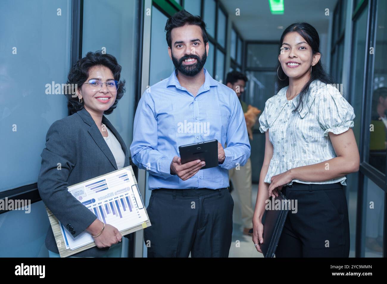 Group of three young indian business people standing in office hallway ...