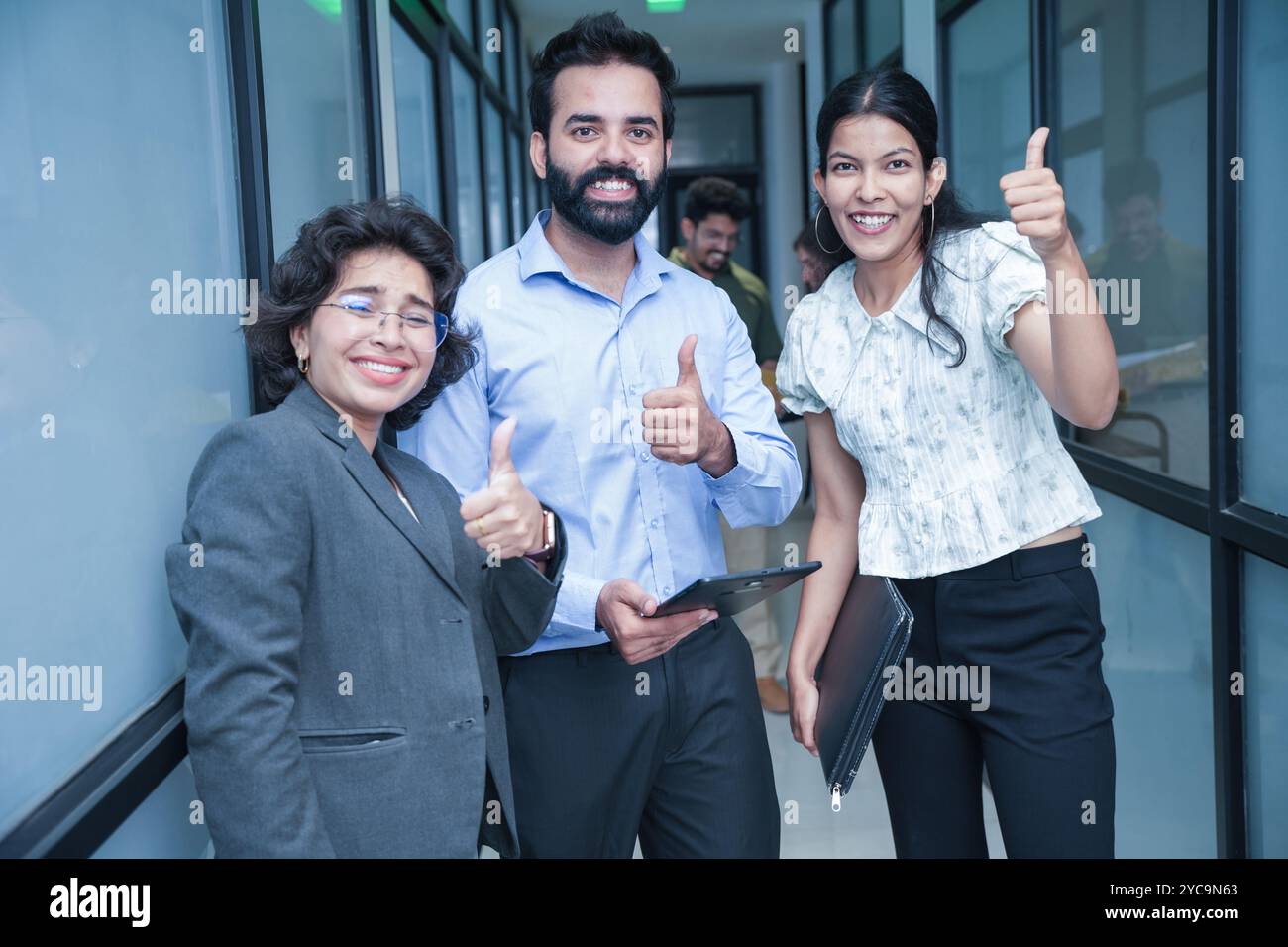 Group of three young indian business people standing in office showing ...
