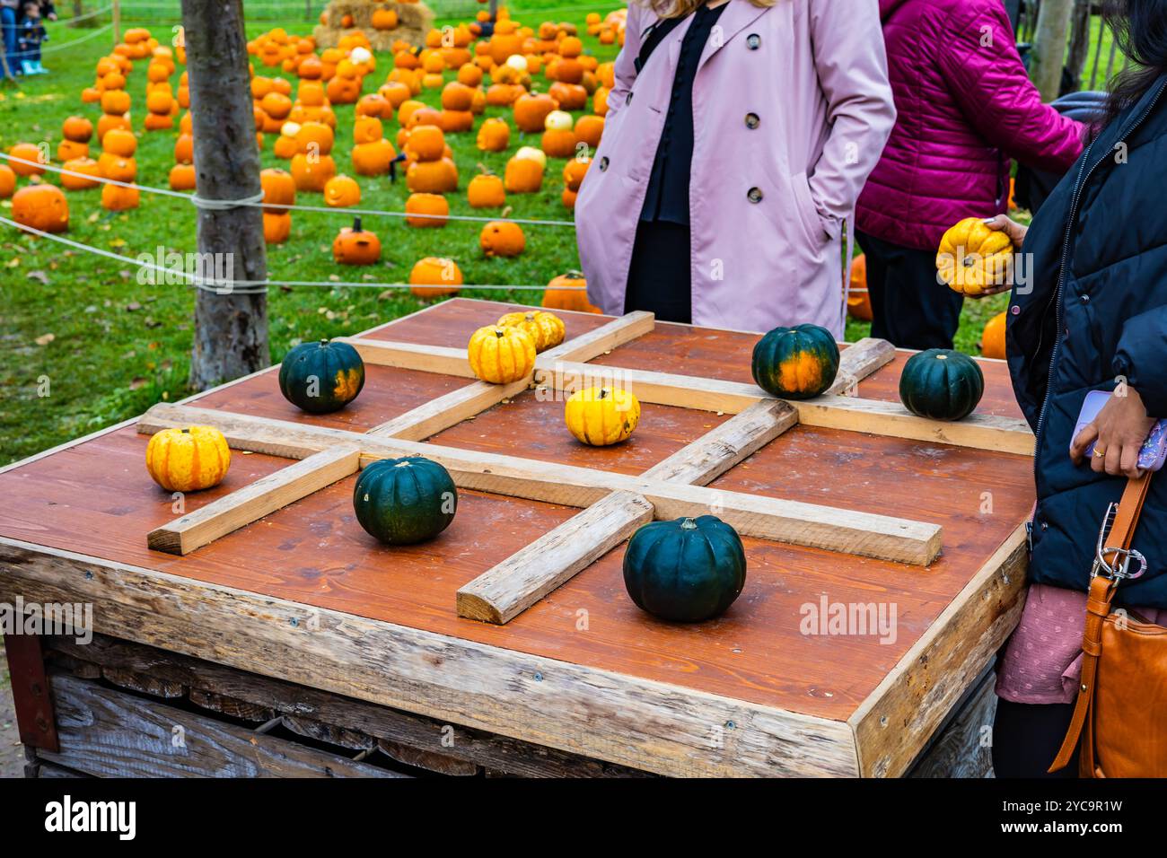 A woman is standing in front of a table with a tic-tac-toe board and ...