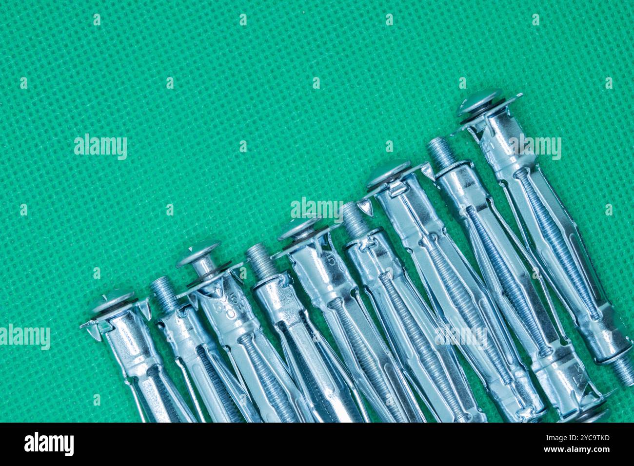 Several new shiny metal dowels are lying on a green background, ready ...