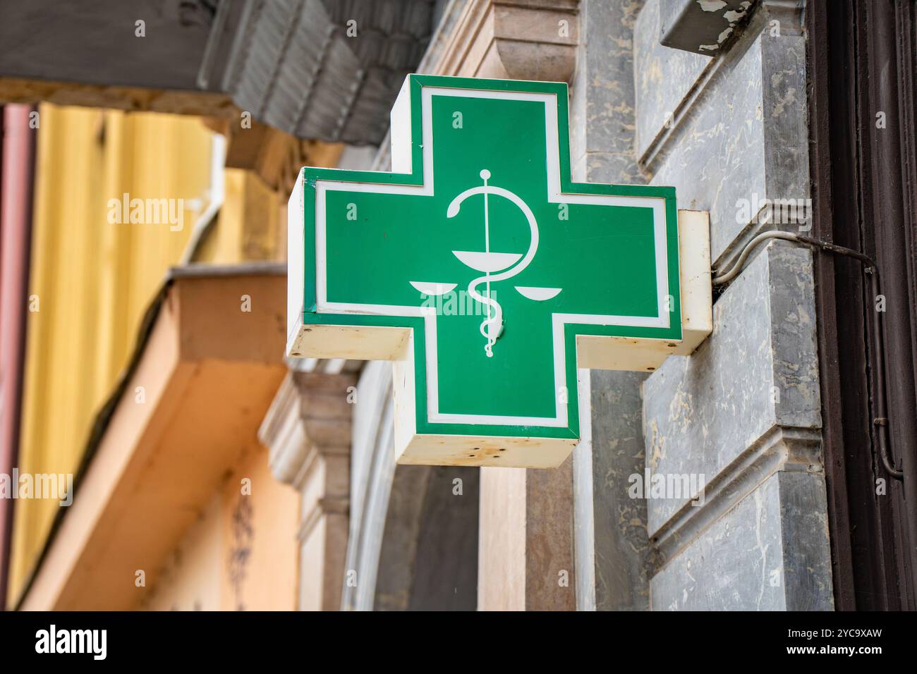 Informative green pharmacy sign featuring caduceus symbol in urban ...