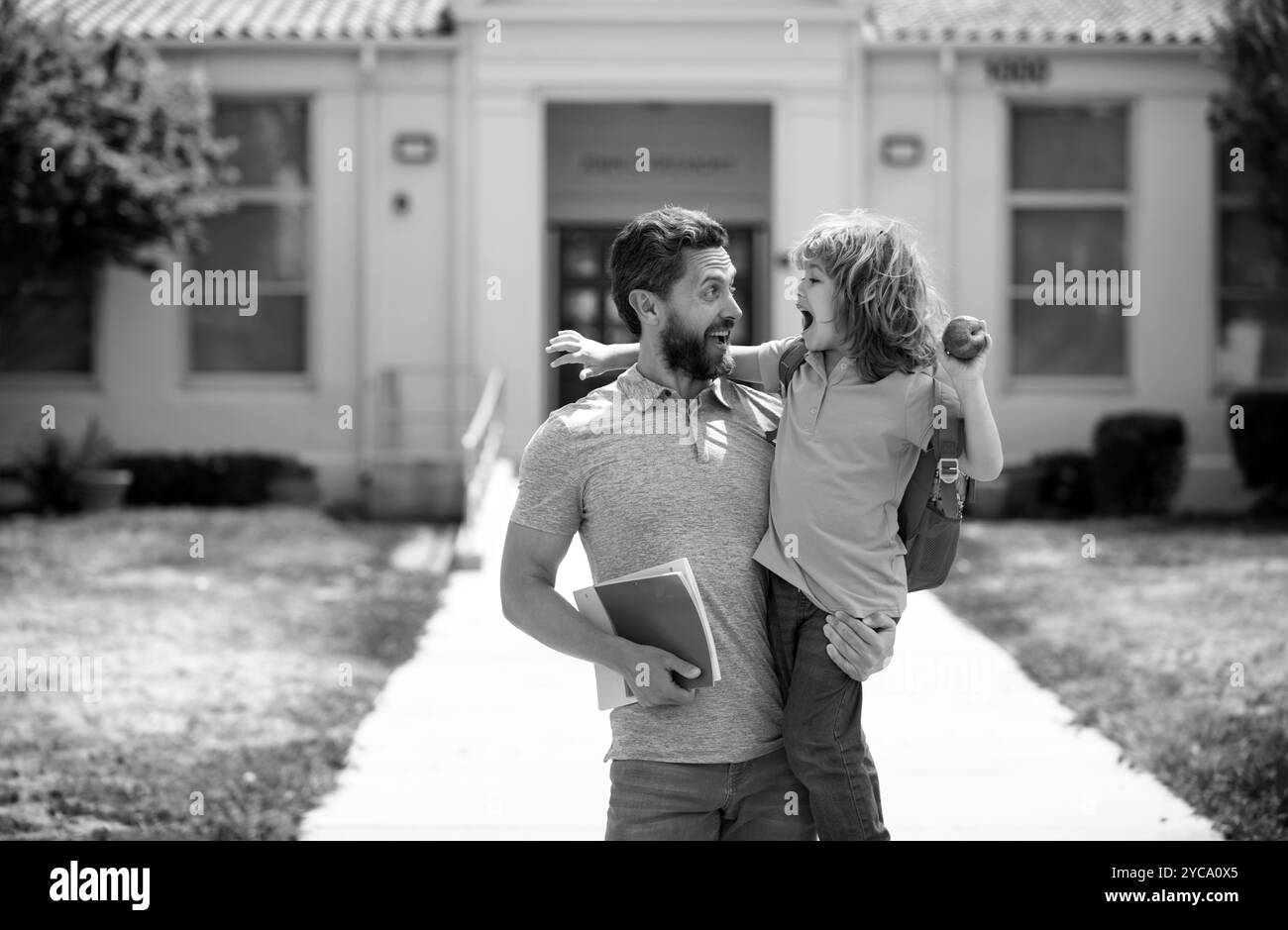 Teacher in t-shirt and cute schoolboy with backpack near school park ...