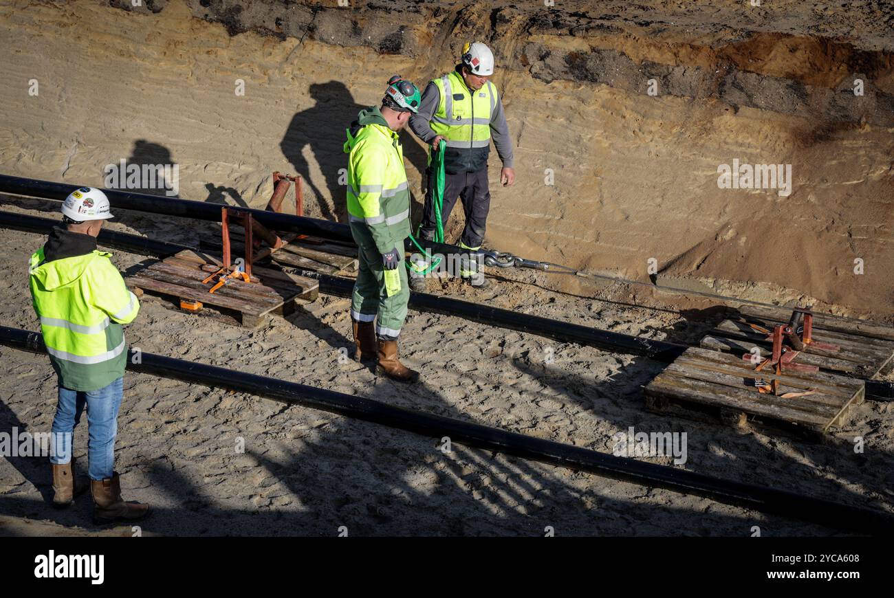 22 October 2024, Lower Saxony, Heeslingen: Workers pull a cable into a ...