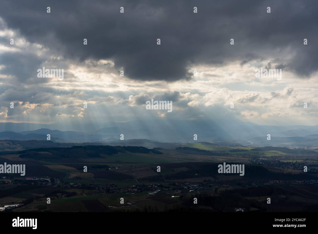 Dramatic sky with sun rays breaking through heavy clouds over a rural ...