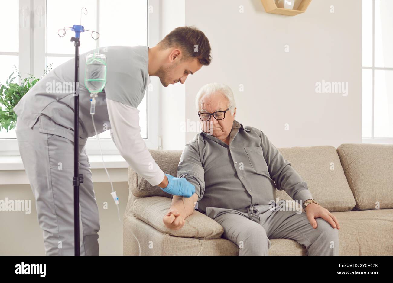 Young nurse help senior patient in receiving IV drip infusion therapy ...