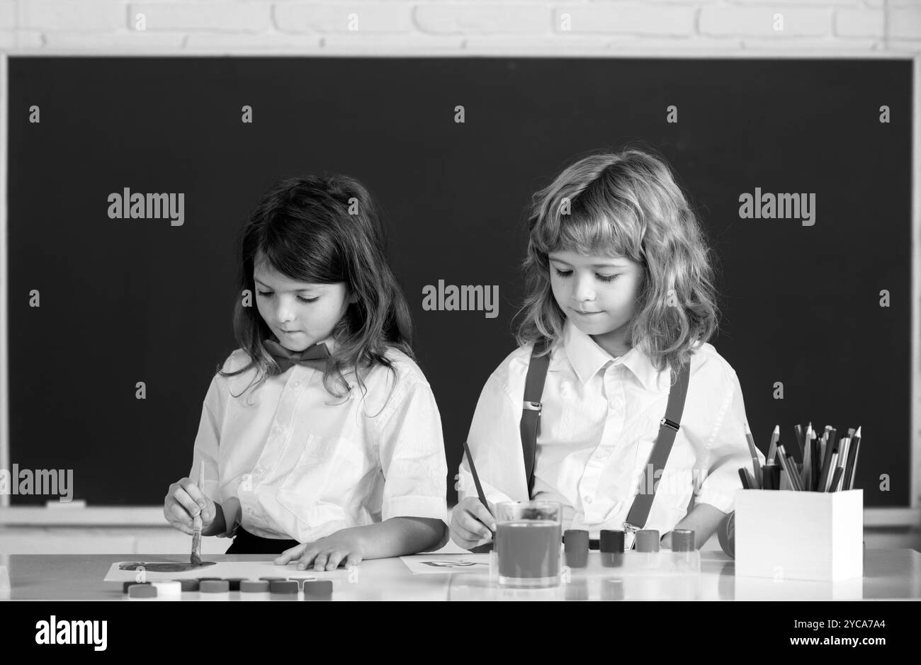 School children girl and boy painting with paints color and brush in ...