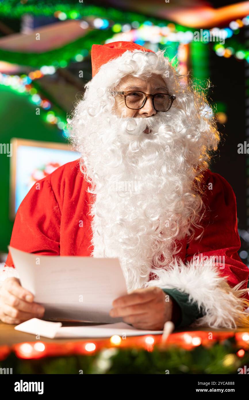 White bearded Santa Claus reviews letters from children by the fire ...