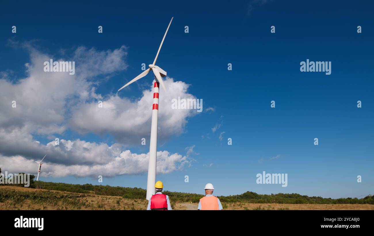 Expert engineers Walking under wind turbine Stock Photo - Alamy