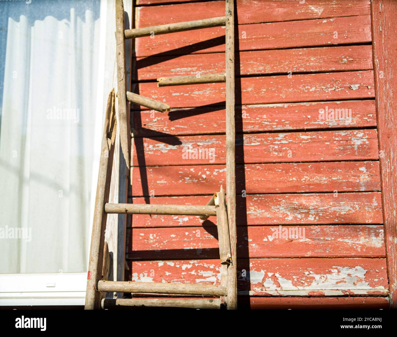 old wooden ladder with broken steps leaned against the wall, outdoor ...