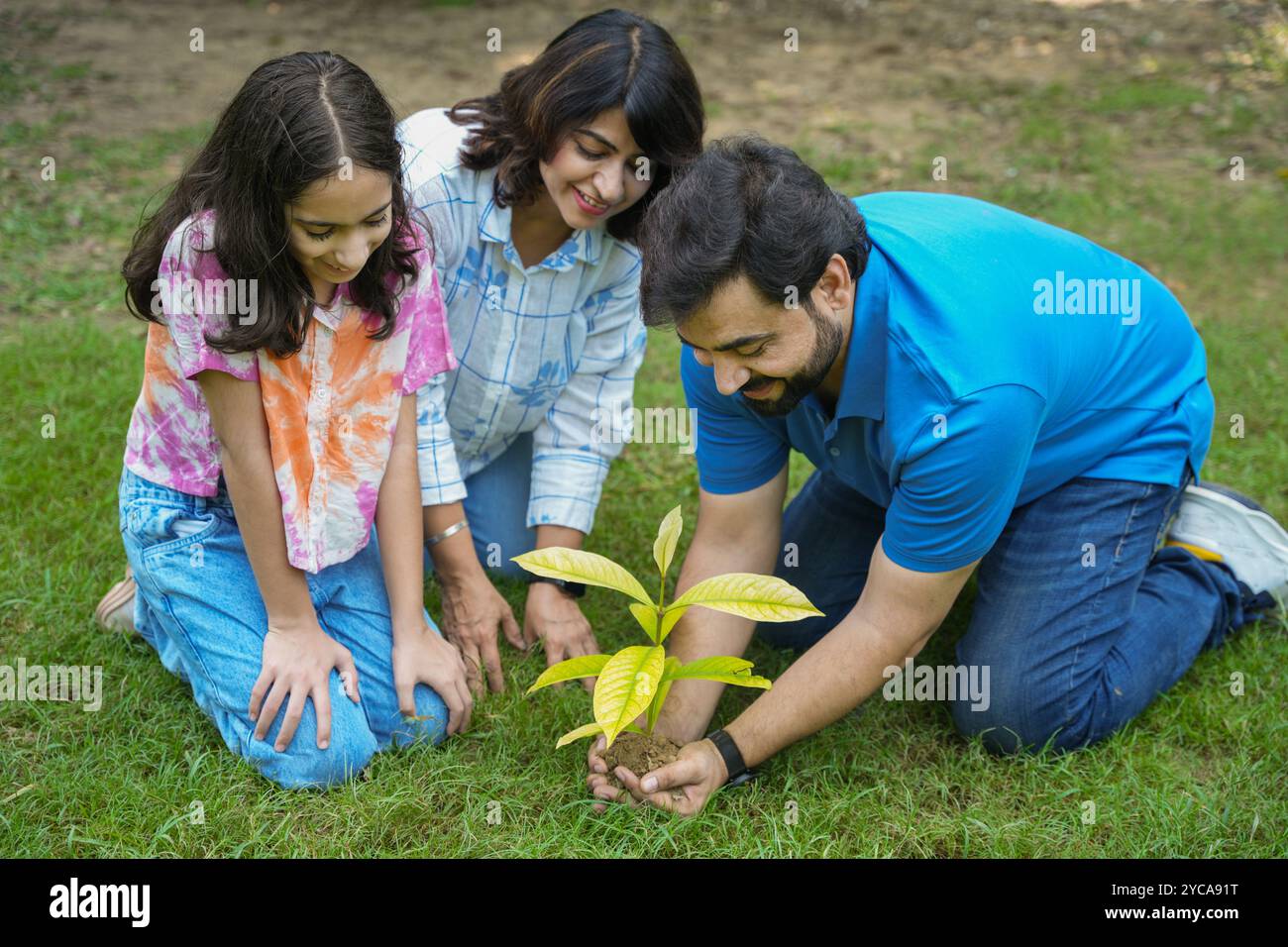 happy young indian family planting tree. concept of environmental ...