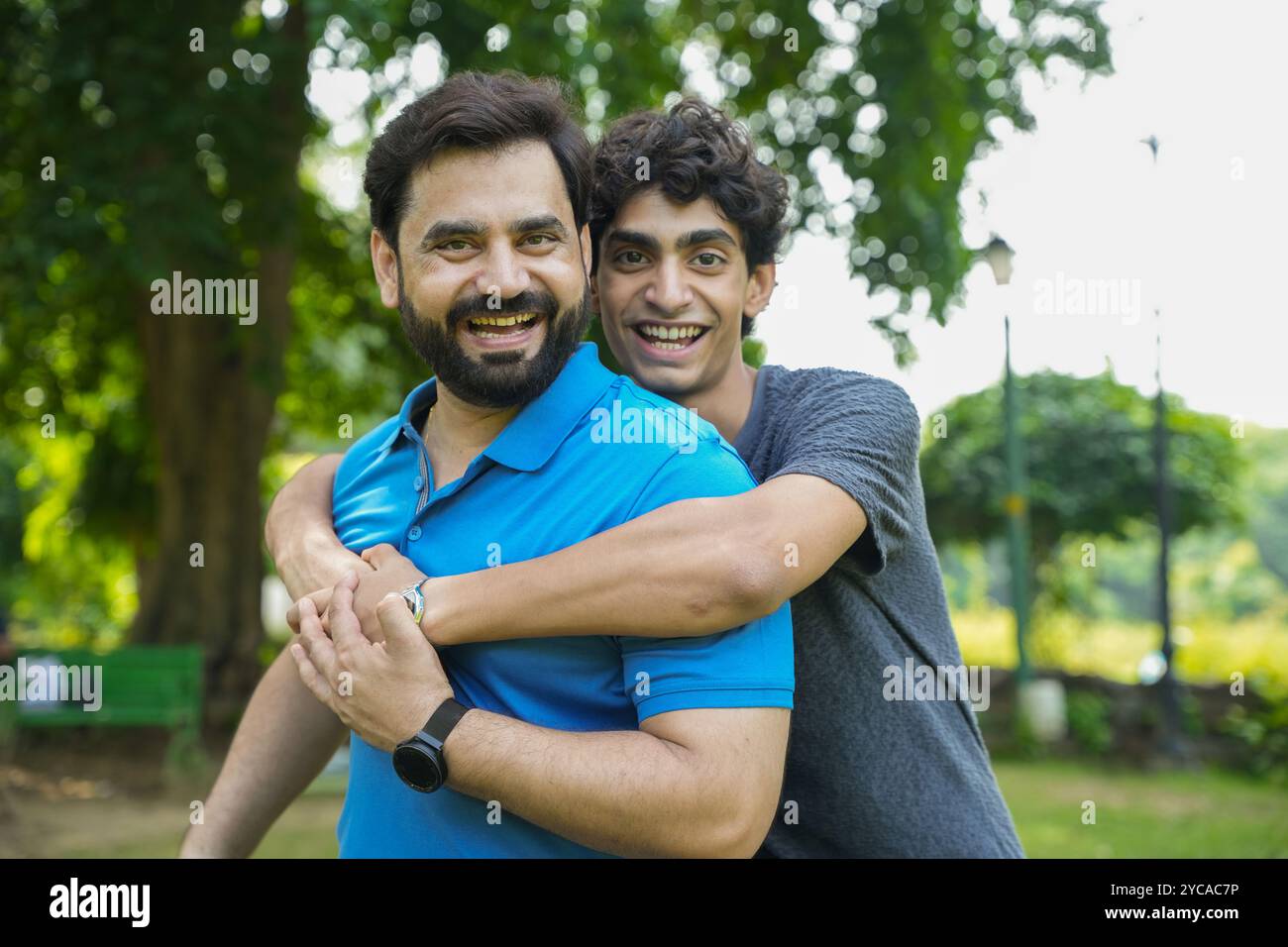 Young happy indian father and son hug each other at summer park ...