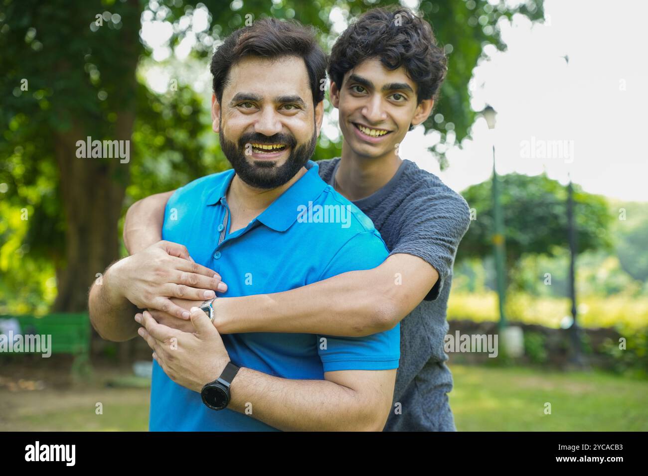 Portrait of young happy indian father and son hug each other at summer ...