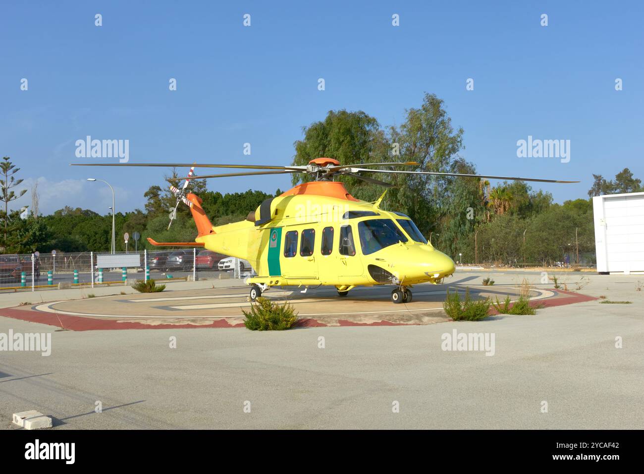 A bright yellow and orange rescue helicopter parked on a concrete ...